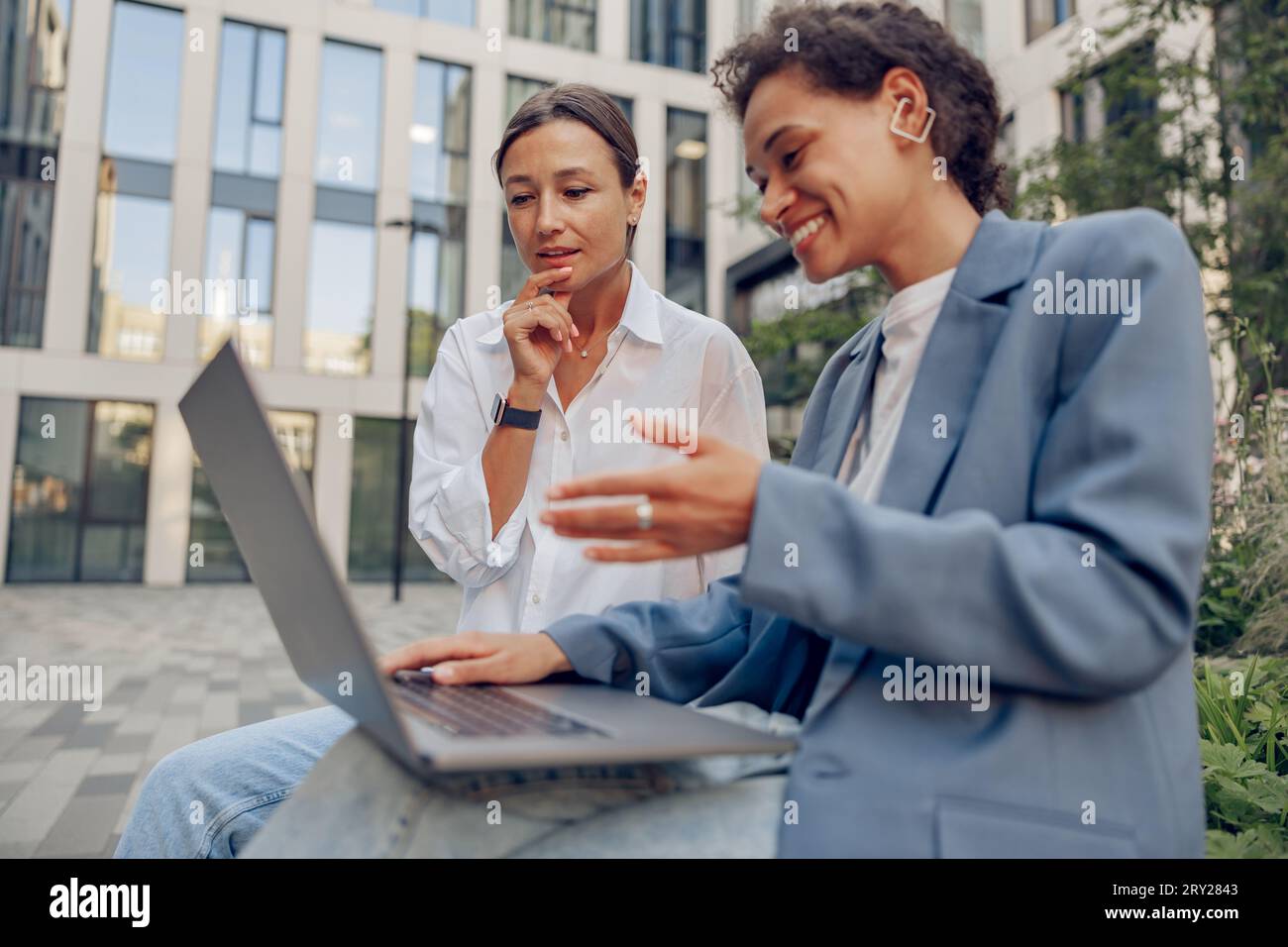 Two business coworkers working outside of office on building background ...