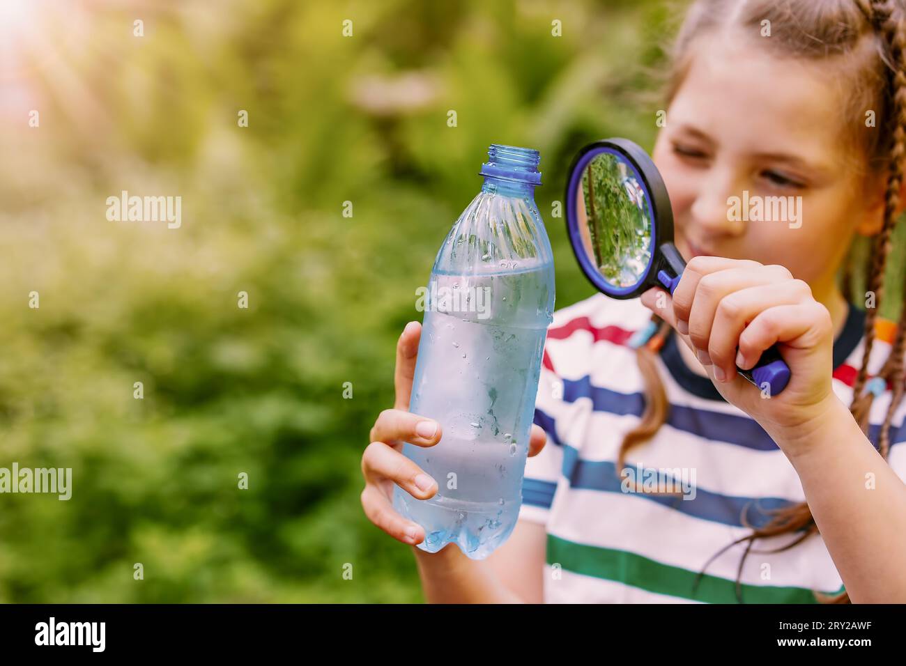 Girl studying water in a bottle with a magnifying glass Stock Photo - Alamy