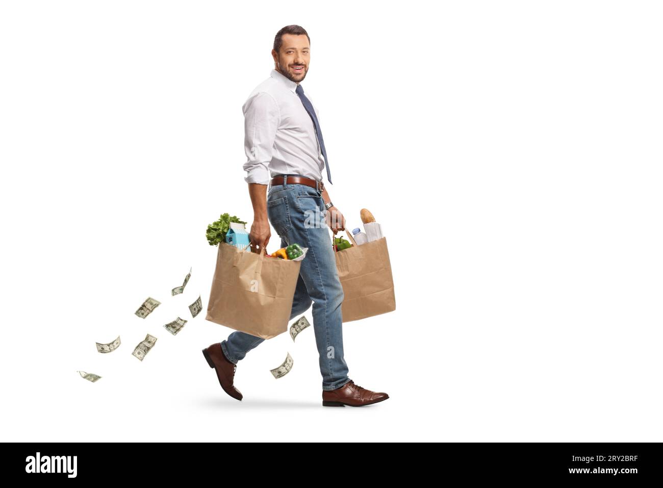 Money falling from grocery bags carried by a man isolated on white ...