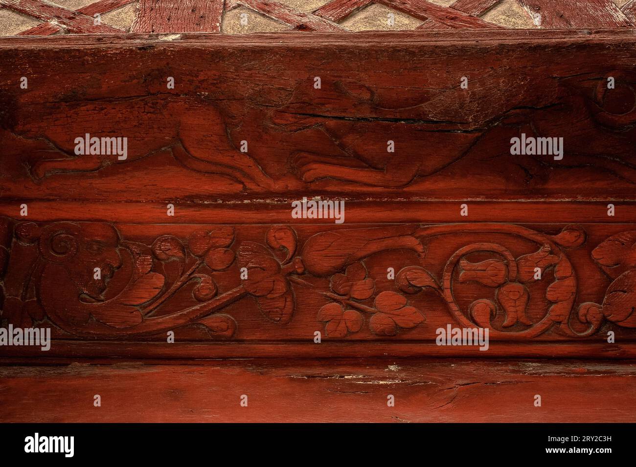 Face of fantastical creature and foliage below two racing greyhounds ...