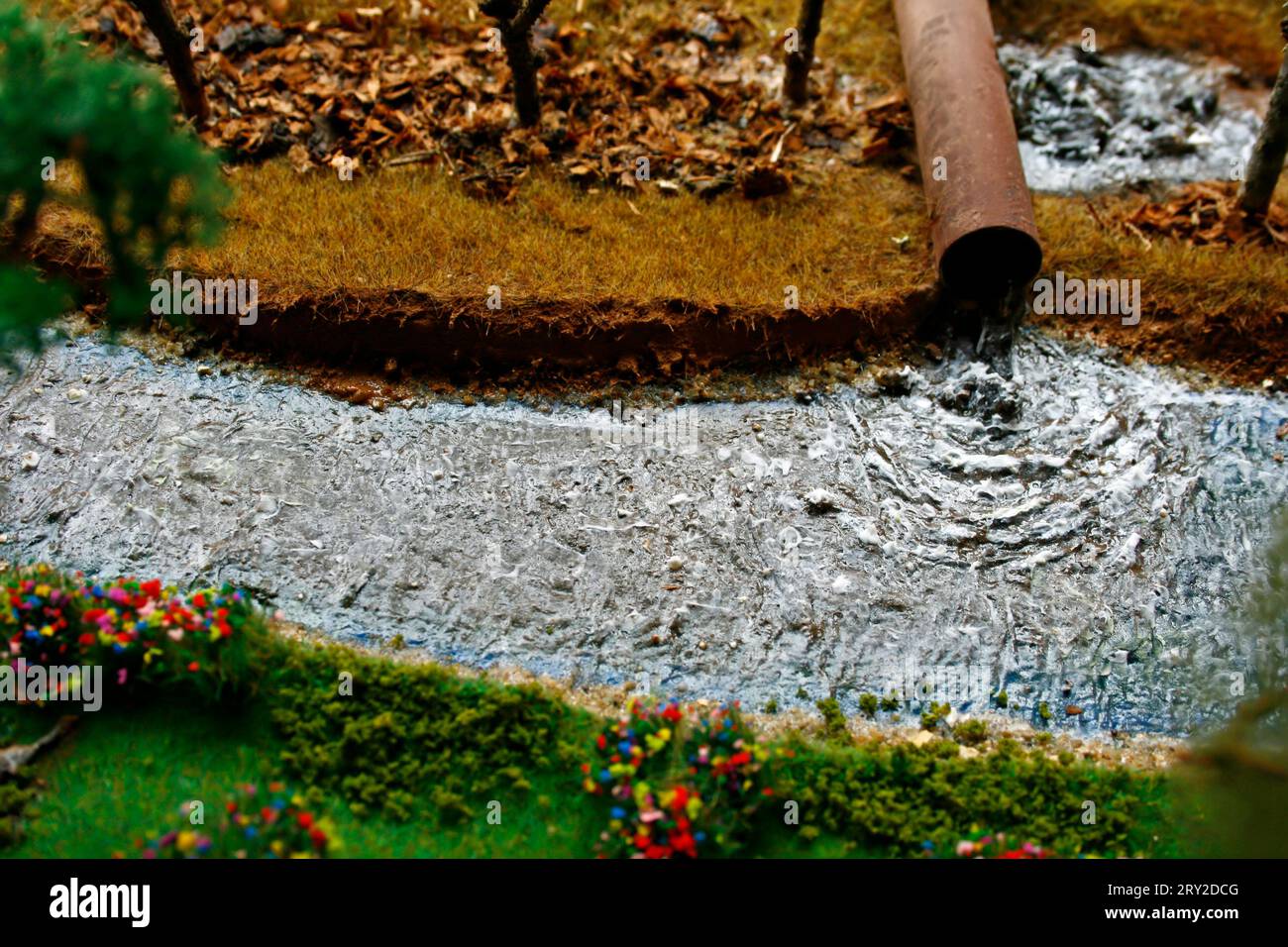Diorama model of a broken sewage pipe discharging into a river with ...