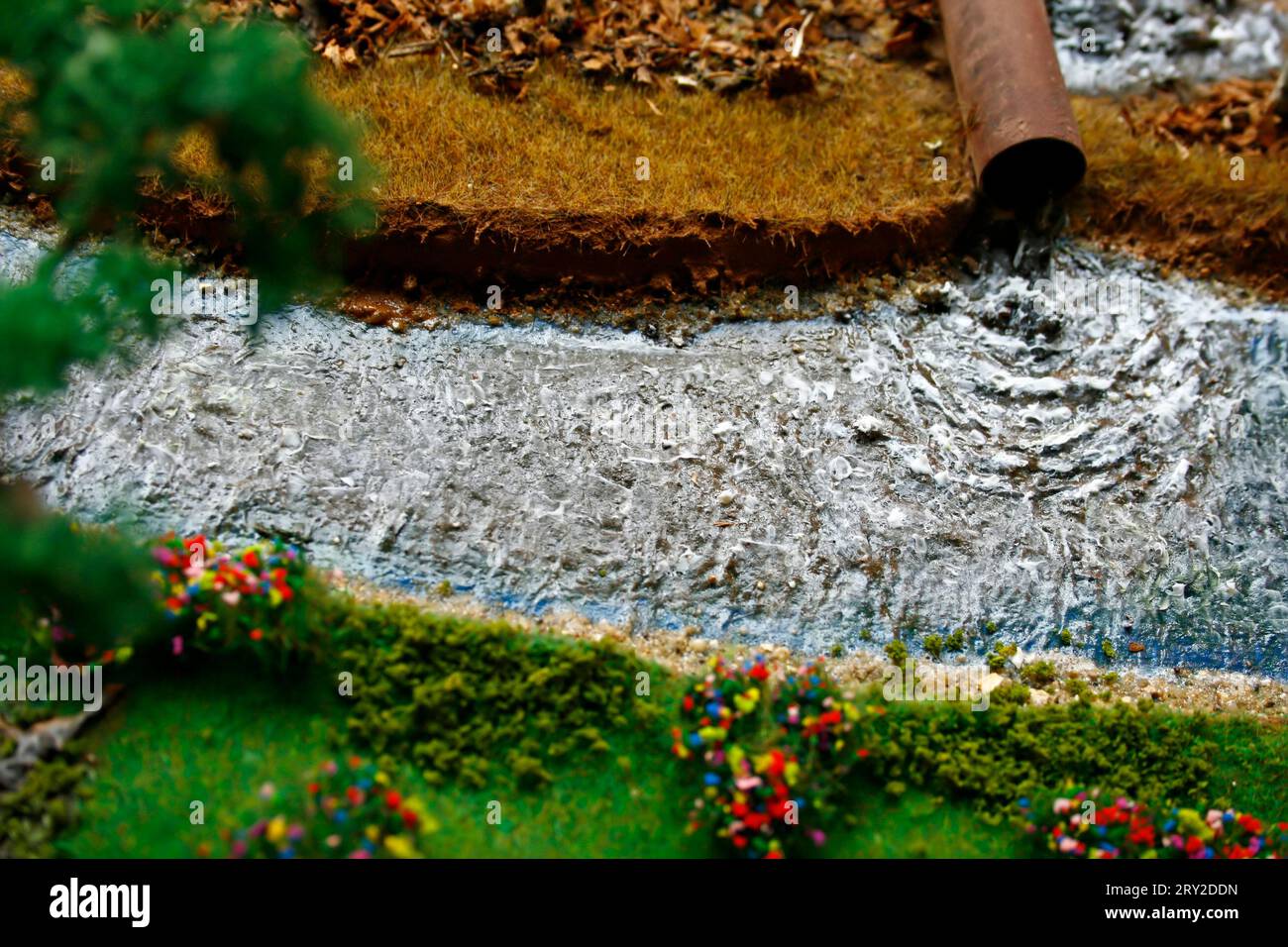Diorama of sewage pipe with effluent flowing into a river and dead and ...