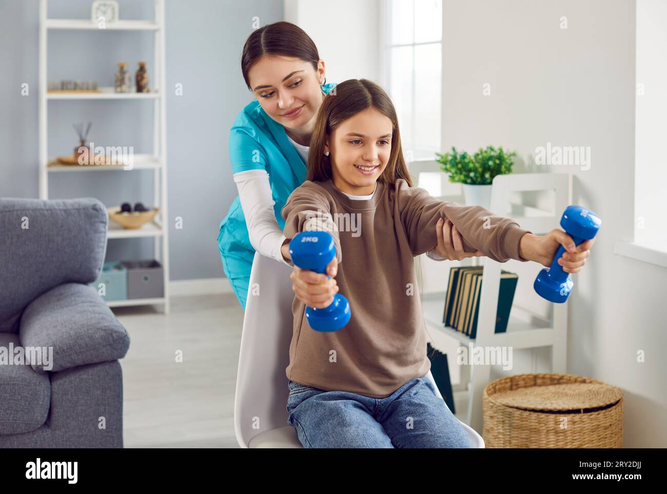 Child girl doing exercise using dumbbells with support from a young ...