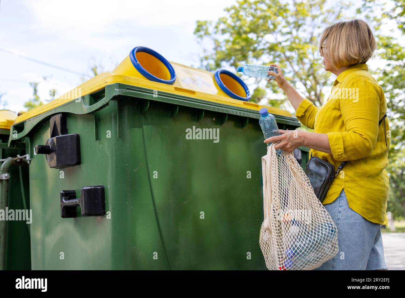 Side view of mature blond woman with eyeglasses throwing plastic ...