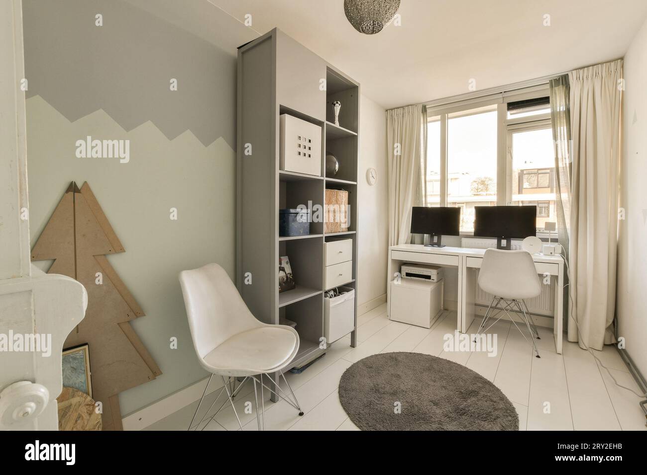 Interior of small room with computers on desk in front of window and ...