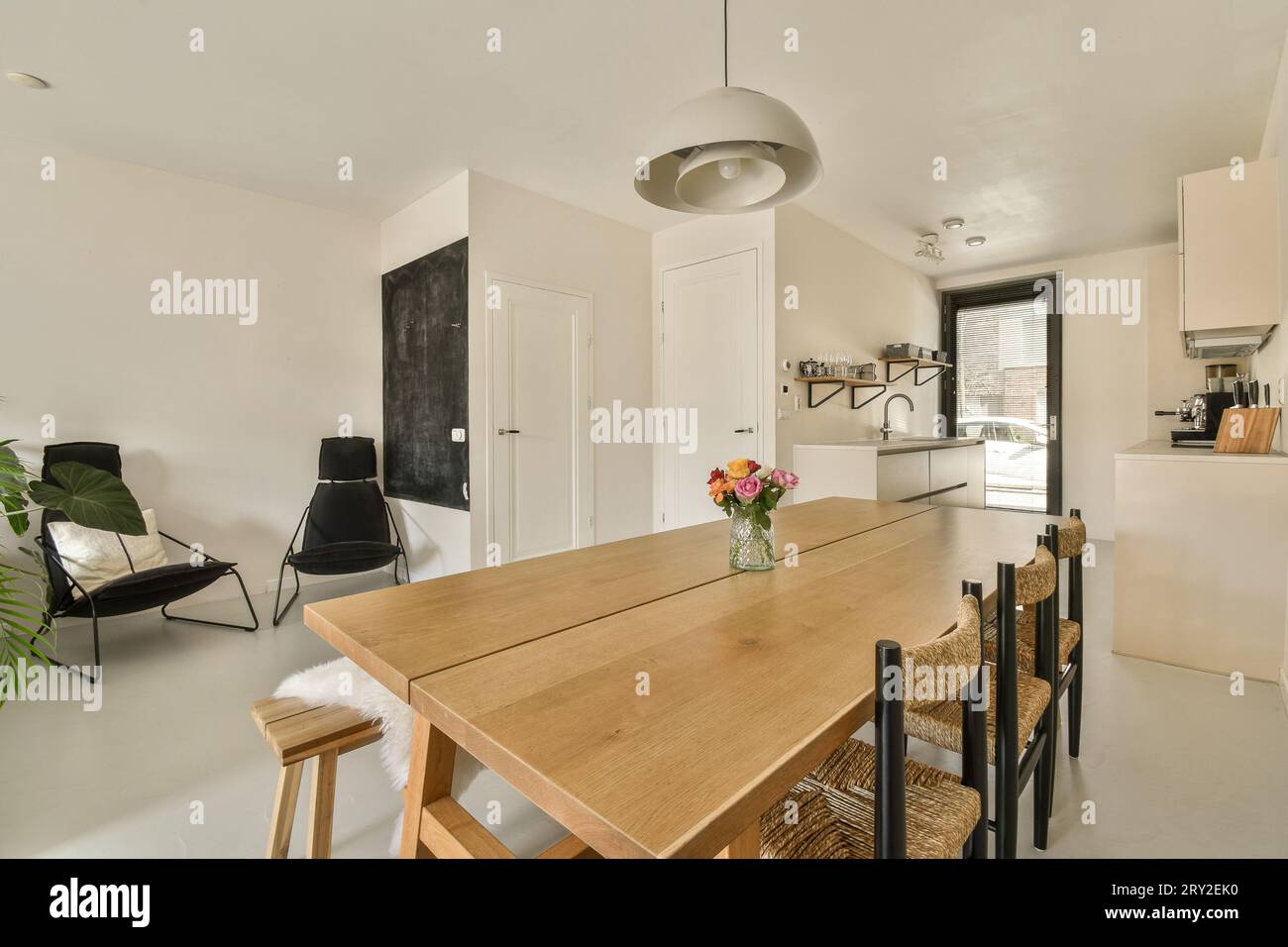 Wooden dining table and chairs arranged in front of open plan kitchen ...