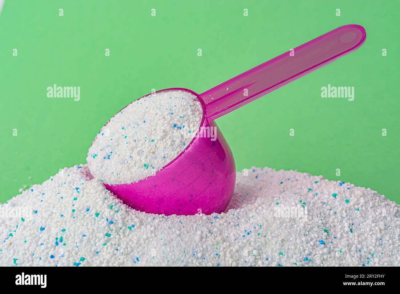 Washing powder in a plastic spoon on a green background. High quality ...