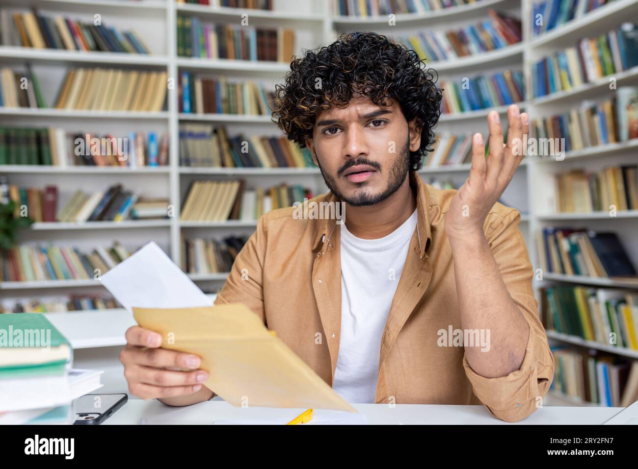 Frustrated young Indian male student sitting in the university library ...