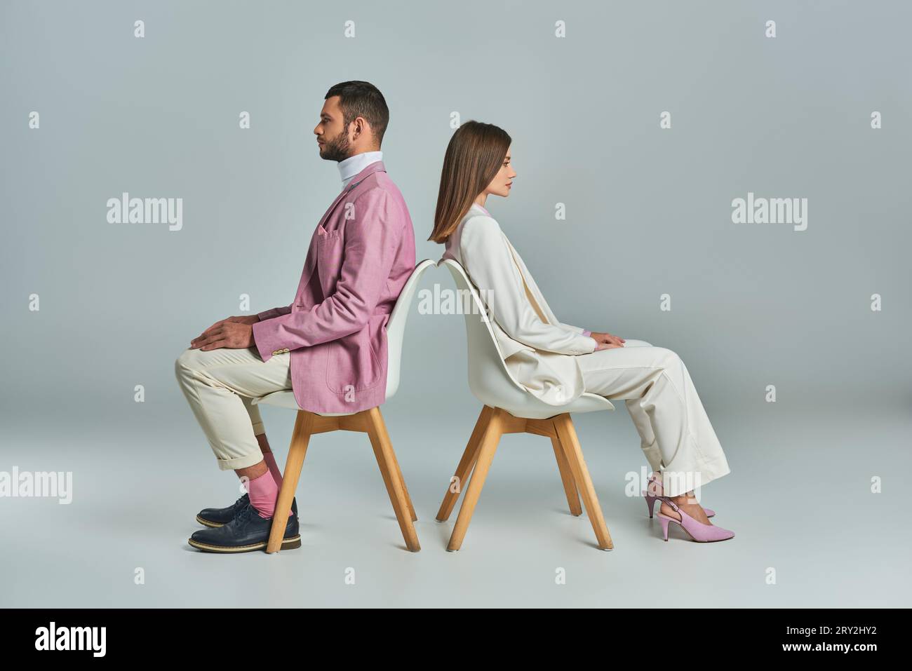 modern couple in business attire sitting back to back in armchairs on ...