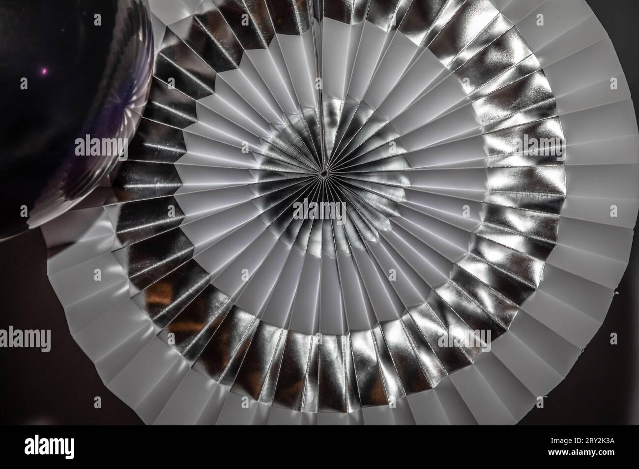 A close-up reveals a silver and white paper accordion, meticulously ...