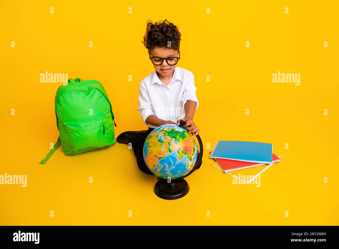 Full length portrait of clever positive schoolkid sit floor look planet ...