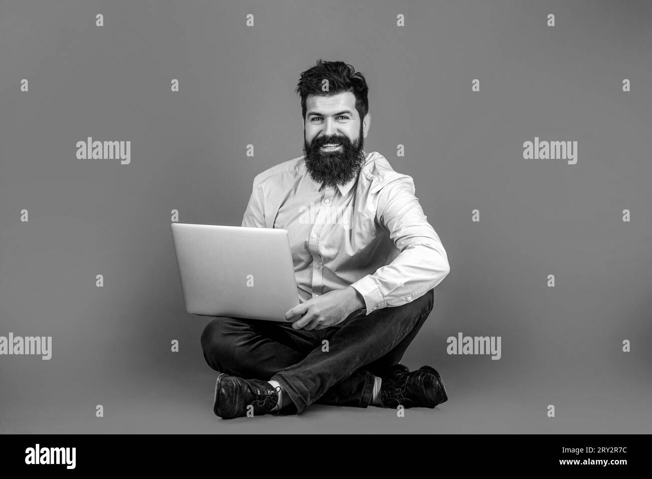 Happy Young Man Sitting On The Floor With And Using Laptop Computer
