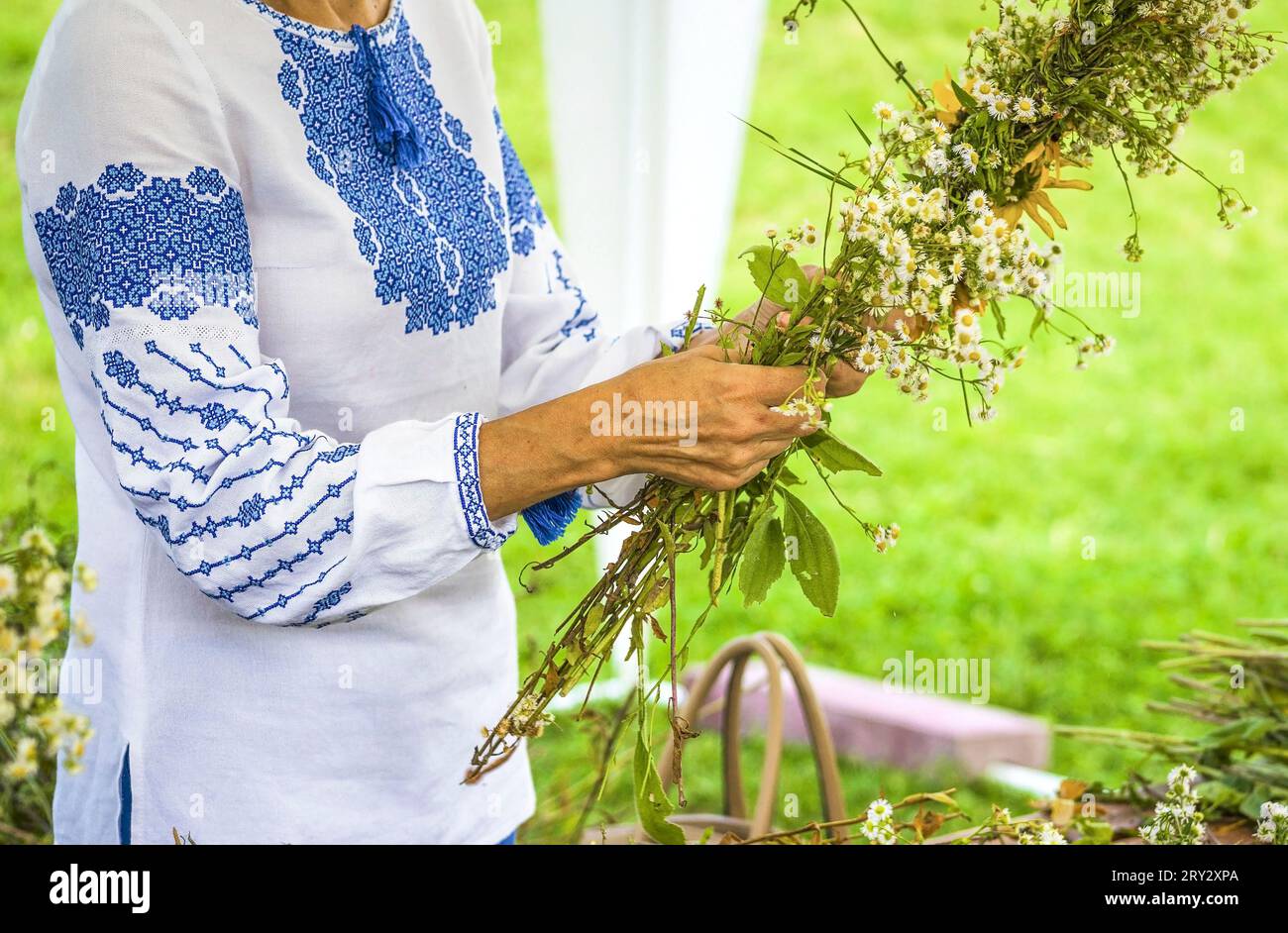 Wild flowers in a hand. Weaving of a wreath from fresh flowers. Green ...
