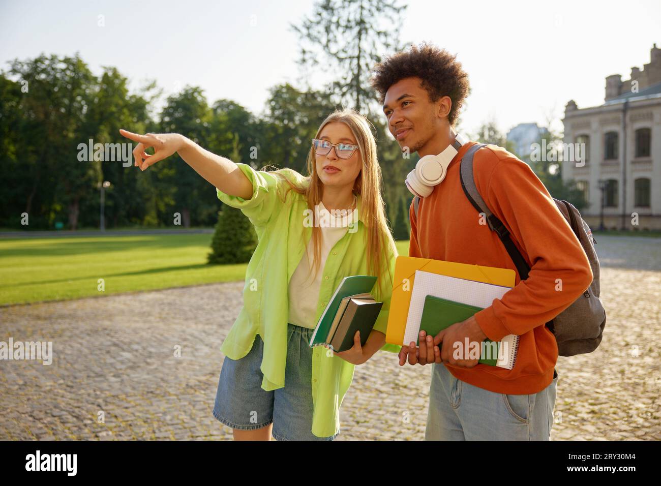 Students gossiping together standing at university campus backyard ...
