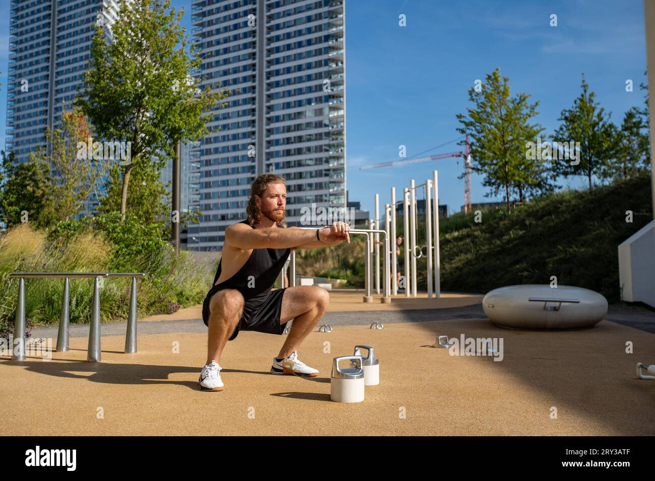 Fit man bending knees to full squat position Stock Photo - Alamy
