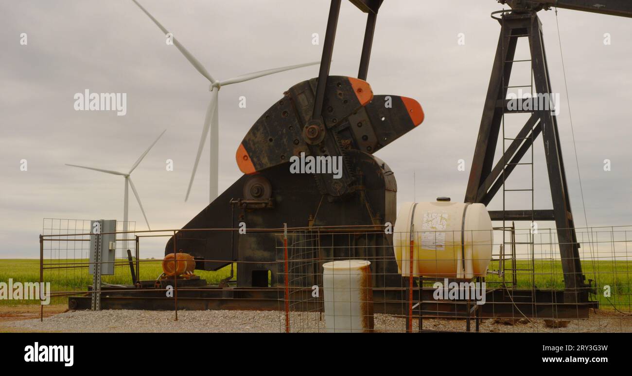 Neighboring oil lifting pumpjack and wind turbines and at work in ...