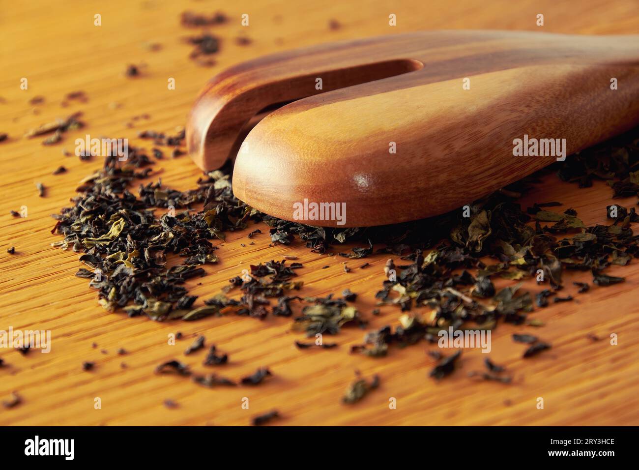 Black and green raw tea leaves scattered on the table with wooden fork ...