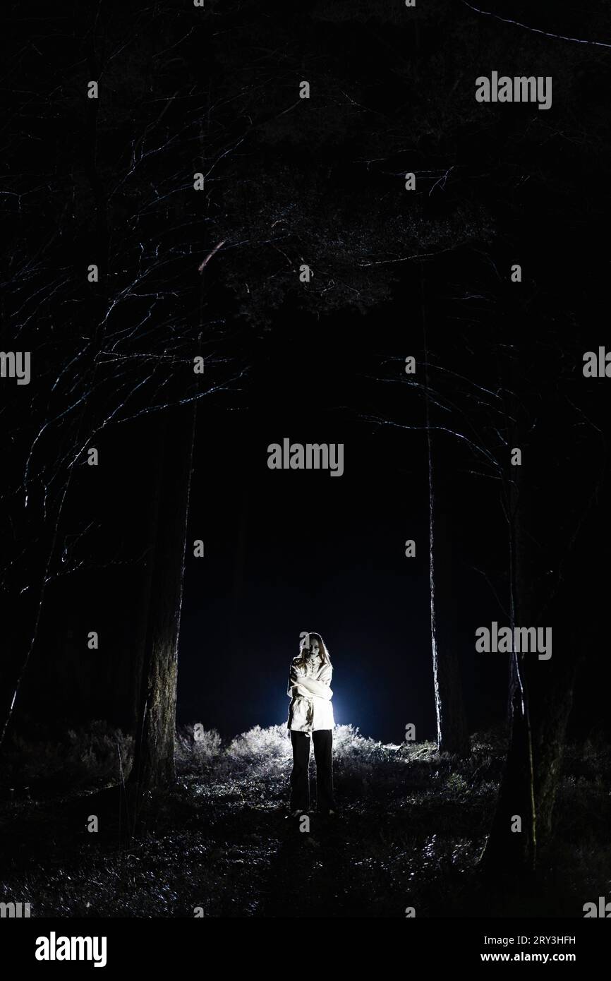 Spooky female ghost standing amidst trees in forest at night Stock ...