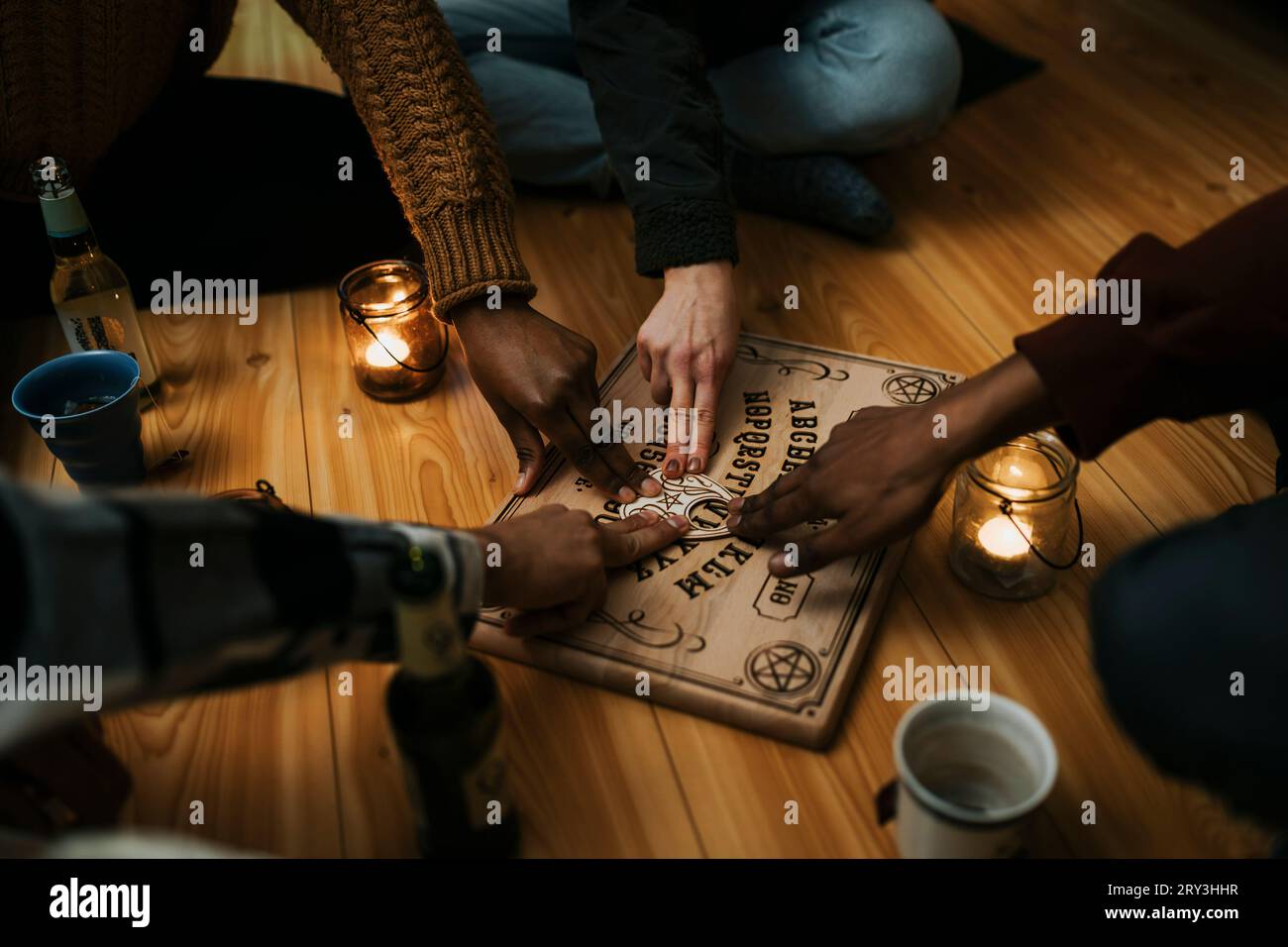 Multiracial Male And Female Friends Using Ouija Board In House Stock