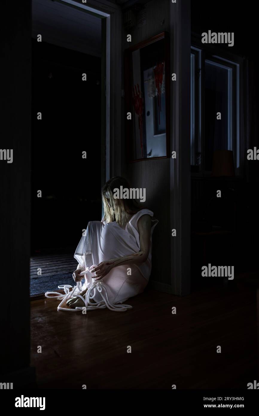 Spooky ghost with rope sitting by doorway in cabin Stock Photo - Alamy