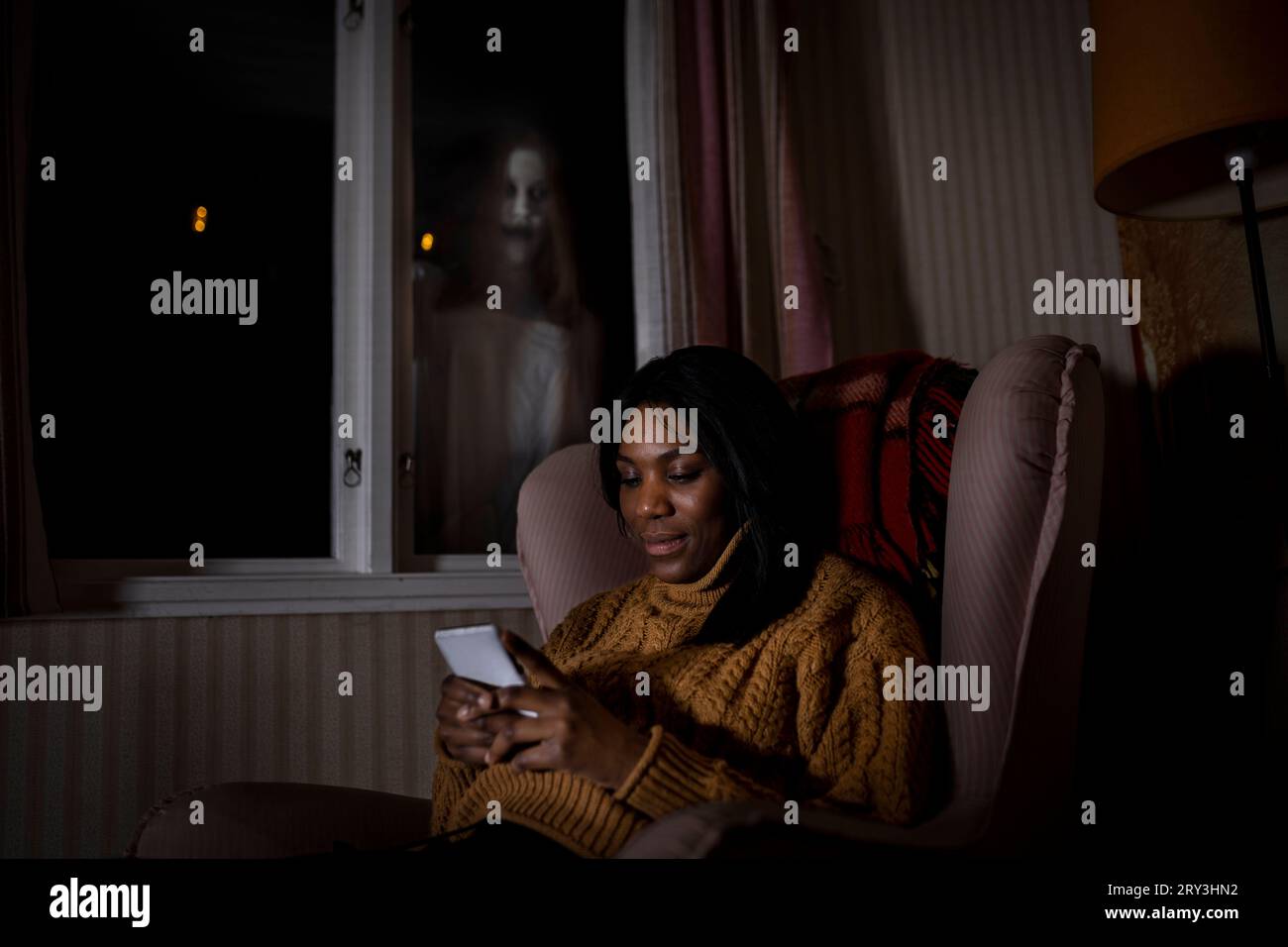 Ghost looking through window at woman using mobile phone in cabin Stock ...