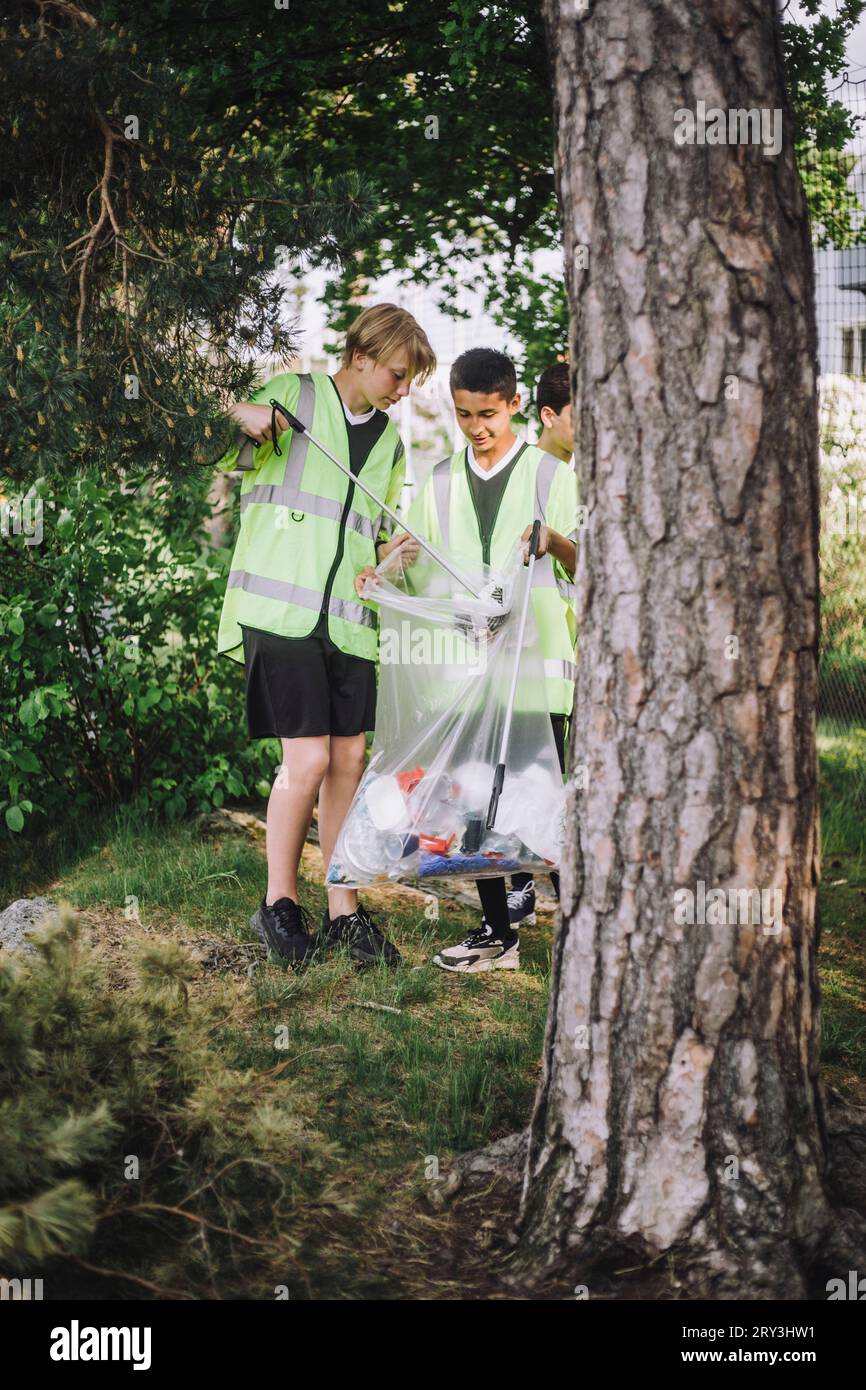 Full length of boys collecting garbage in plastic bag Stock Photo - Alamy