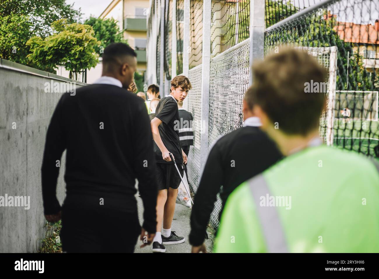 Portrait of teenage boy looking back while walking with friends Stock ...