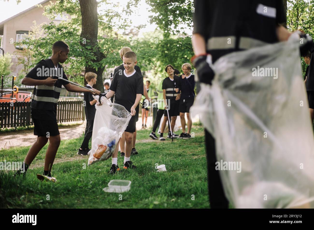 Smiling boy collecting garbage with friend Stock Photo - Alamy