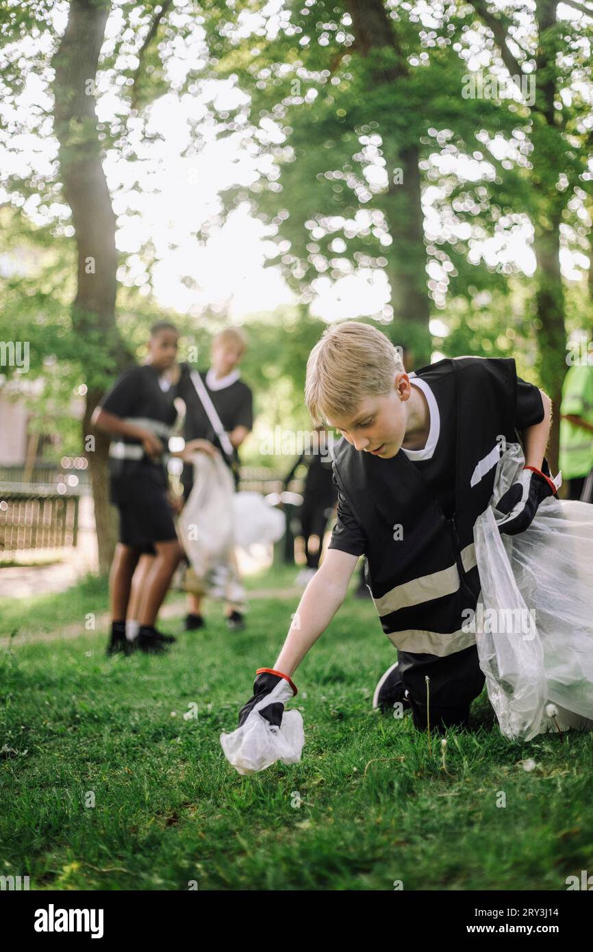 Blond boy collecting plastic in garbage bag Stock Photo - Alamy