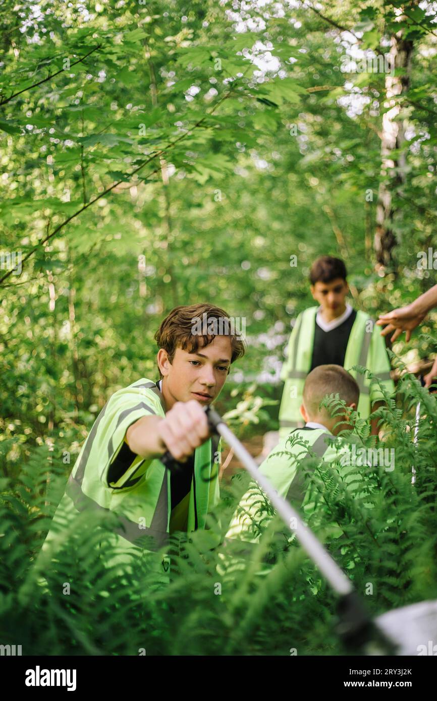 Teenage boy picking plastic garbage from green plant Stock Photo - Alamy