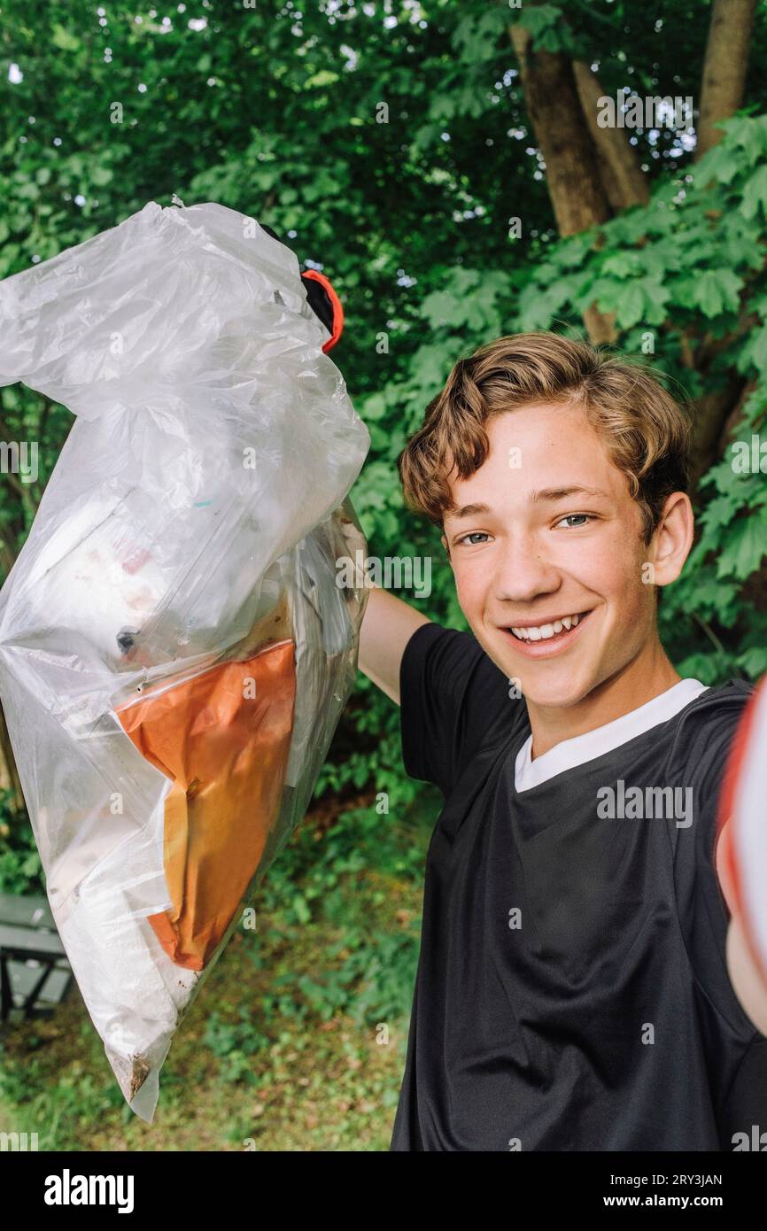 Portrait of happy teenage boy showing garbage bag with plastic Stock ...