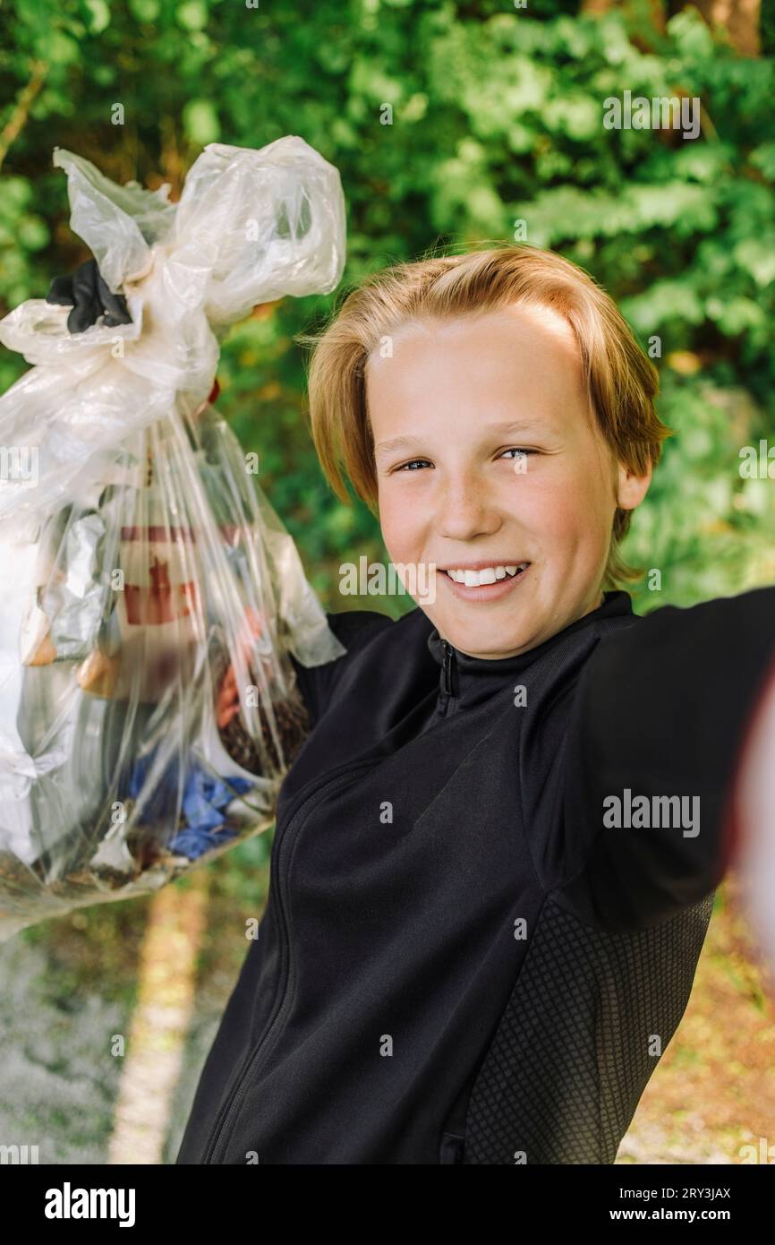 Portrait of smiling boy taking selfie with garbage bag Stock Photo - Alamy