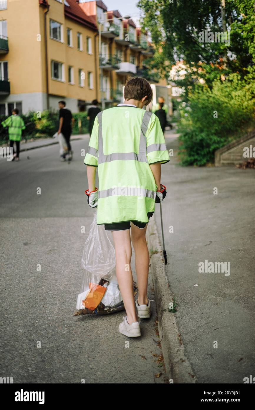 Full length rear view of teenage boy wearing reflective clothing while ...