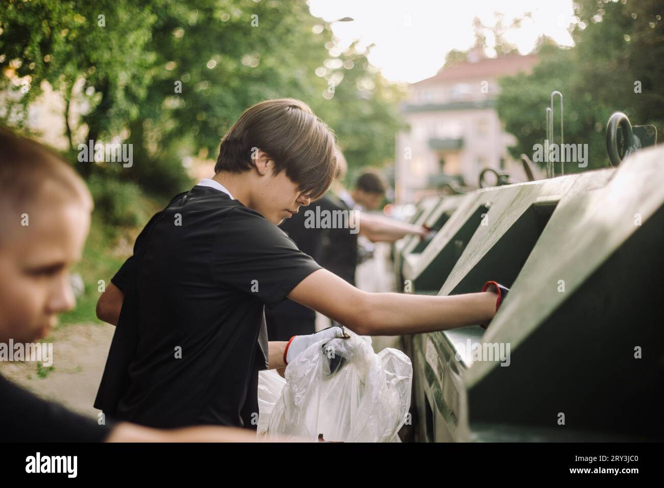 Teenage boy putting garbage in recycling bin Stock Photo - Alamy