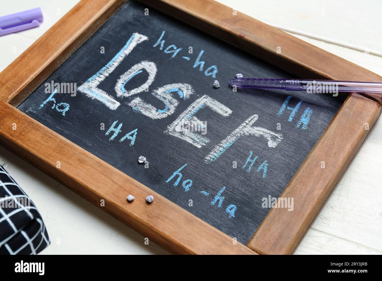 Chalkboard with word LOSER and school stationery on white wooden ...