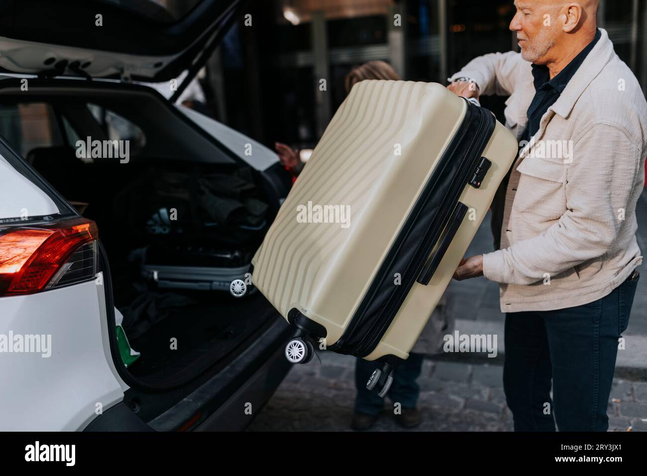 Side view of senior man loading luggage in car trunk Stock Photo - Alamy
