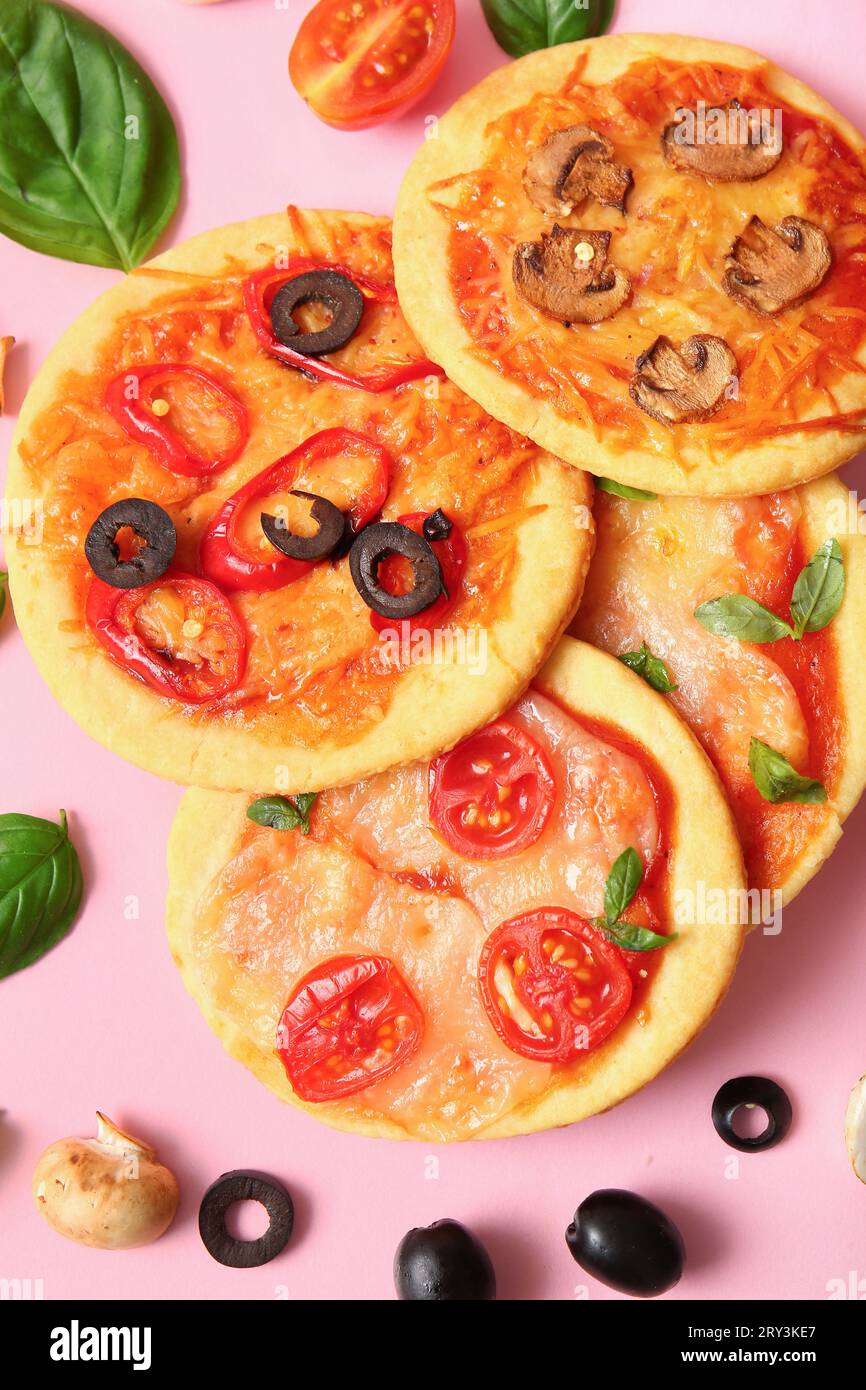 Different tasty mini pizzas and ingredients on pink background Stock ...