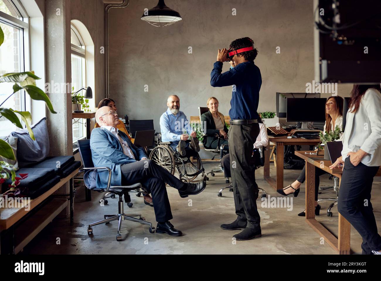 Male and female colleagues watching businessman wearing VR simulator at ...