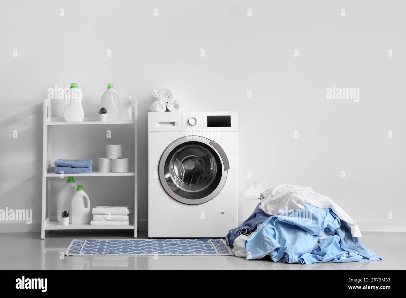 Washing machine, shelving unit and pile of dirty laundry near white ...