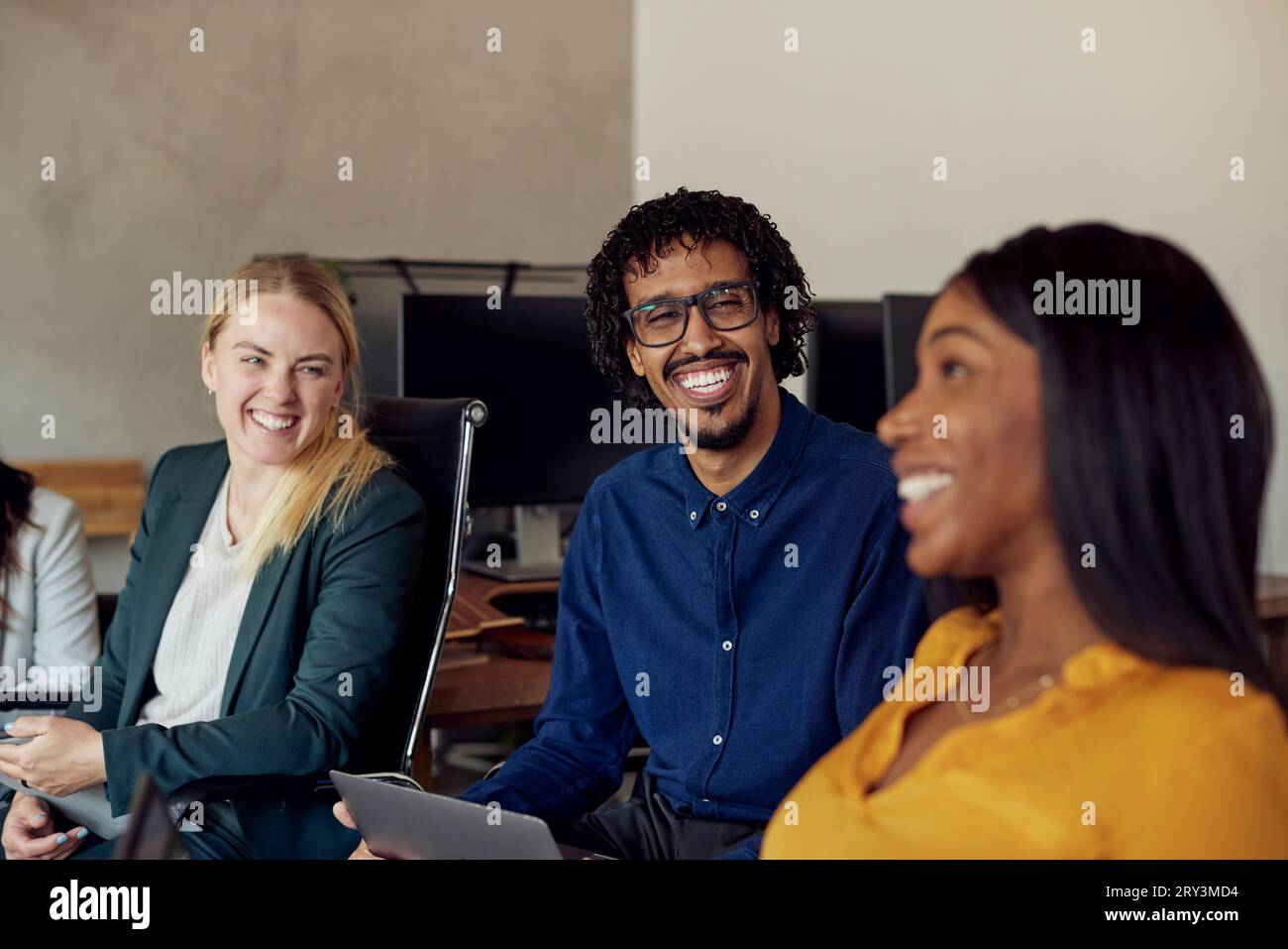 Happy multiracial colleagues sitting together at office Stock Photo - Alamy