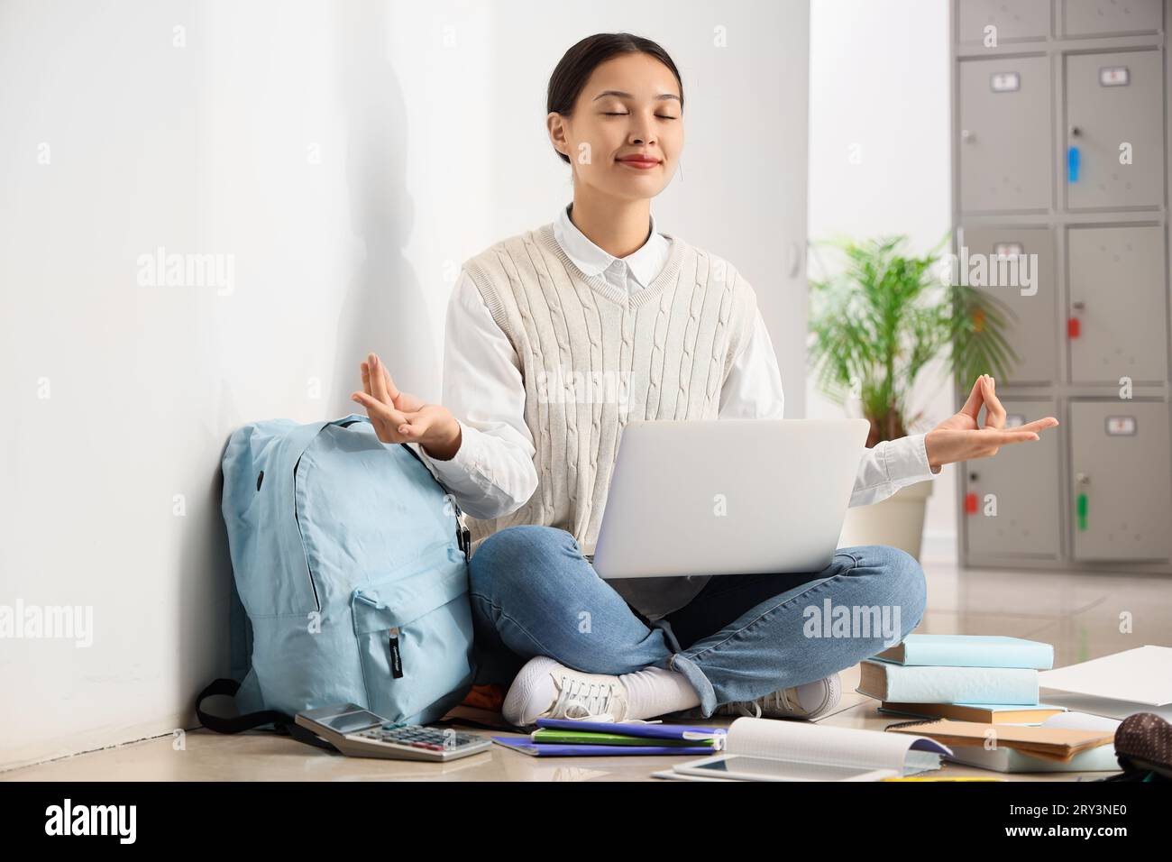 Female Asian student with laptop meditating at university hall Stock ...