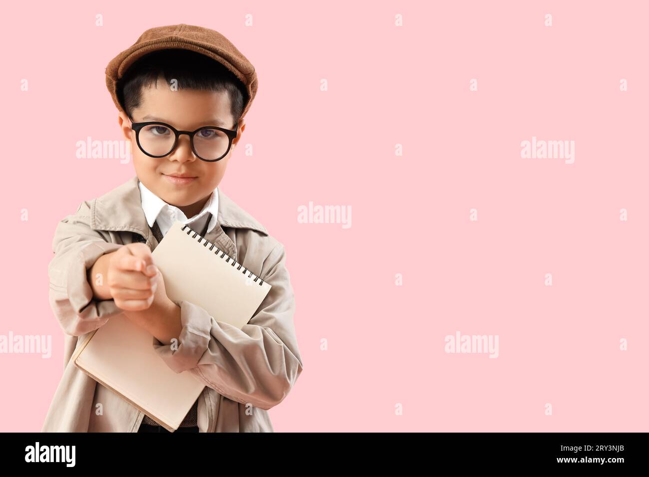 Cute little detective with notebook pointing at viewer on pink ...