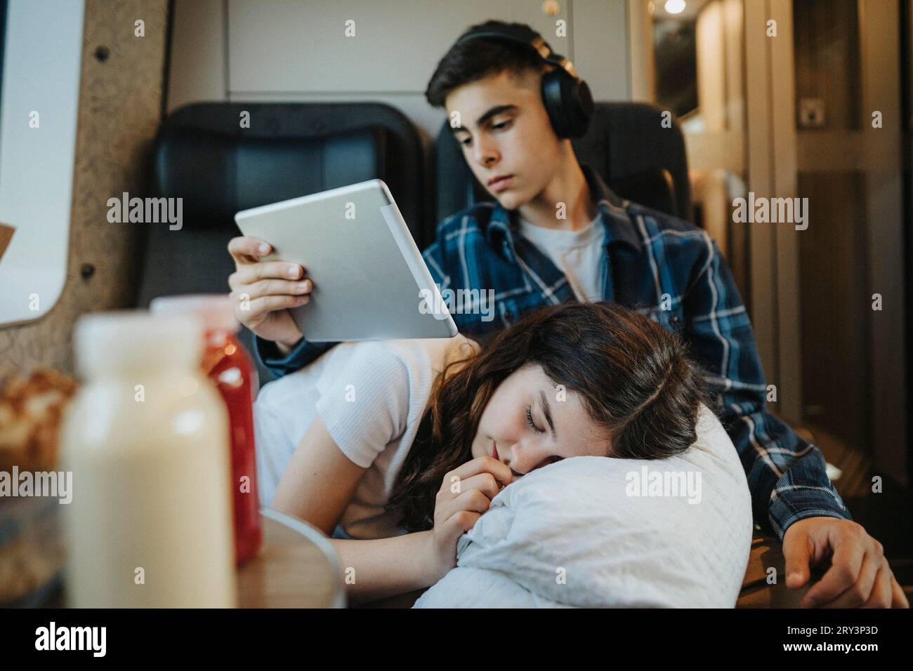 Boy holding tablet PC with sister taking nap in train Stock Photo - Alamy