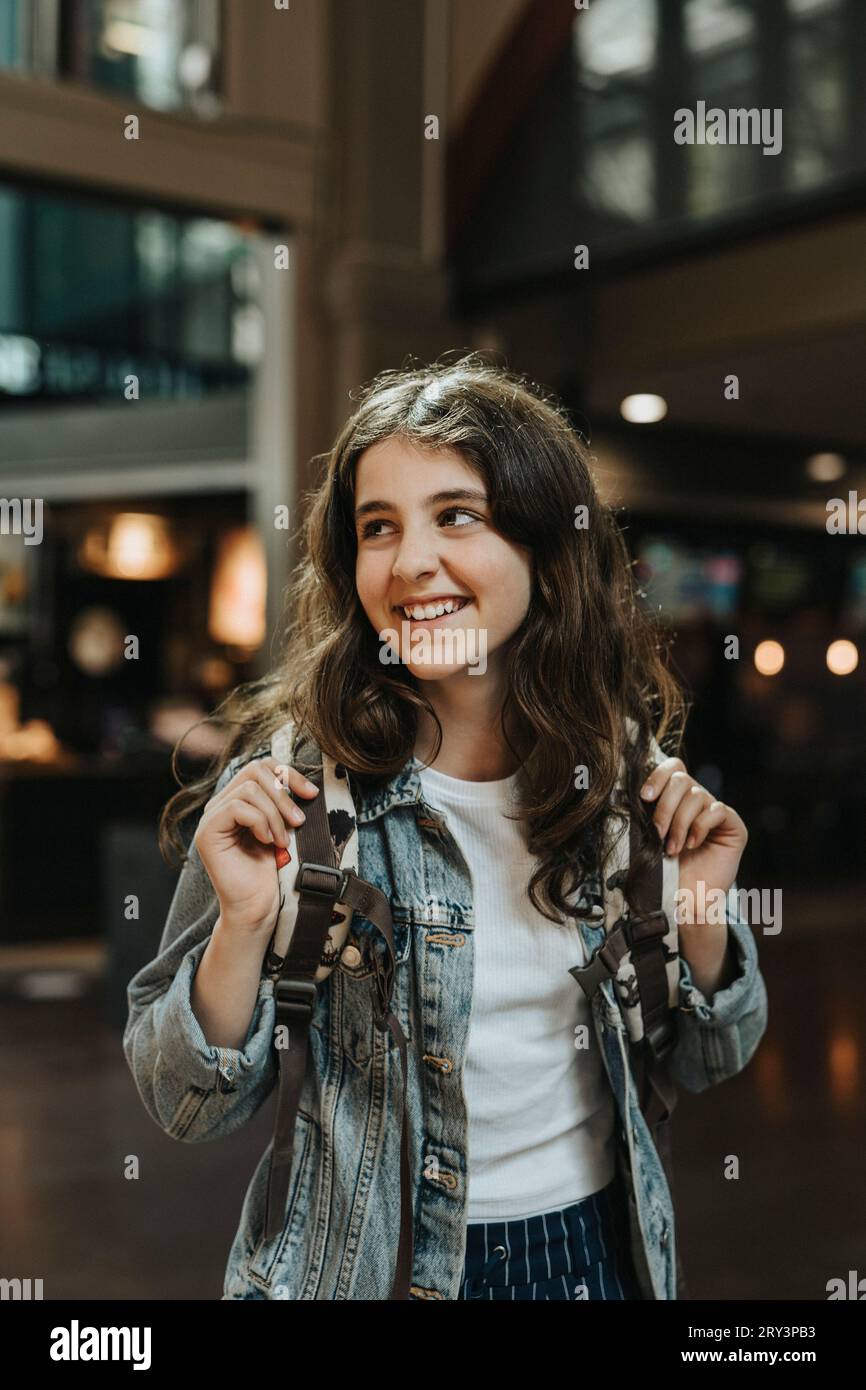 Happy girl with backpack standing at station Stock Photo - Alamy