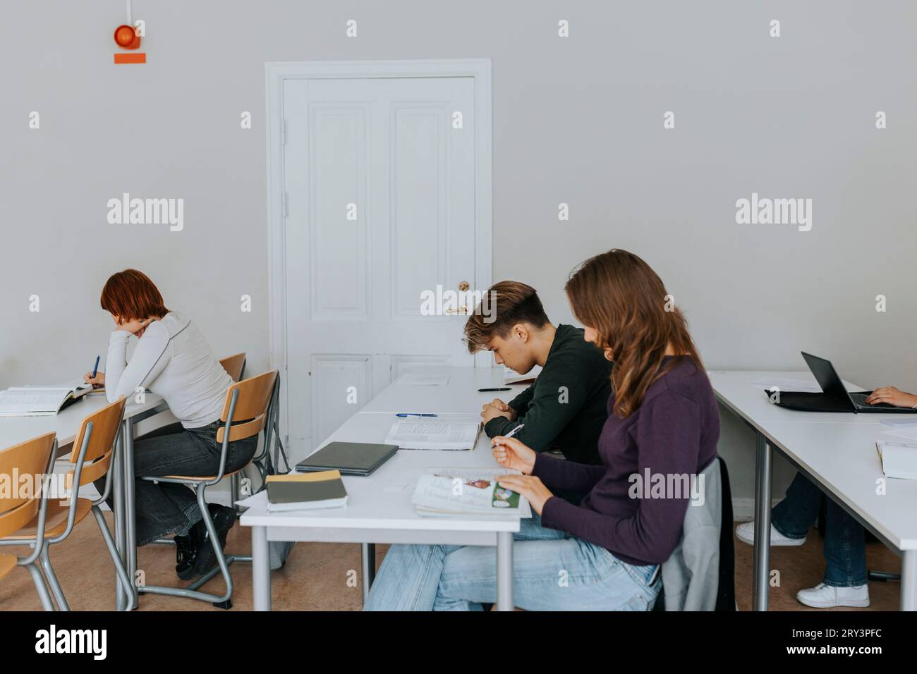 Side view of students studying at desks in classroom Stock Photo - Alamy