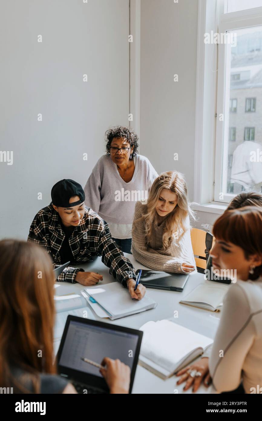 Teacher standing behind students in classroom Stock Photo - Alamy