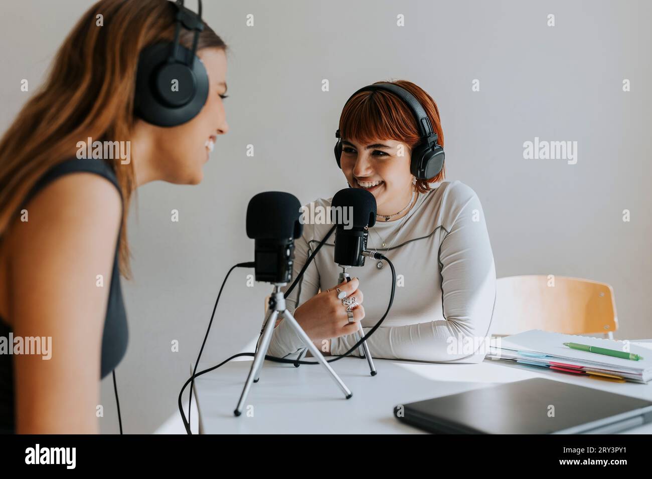 Happy teenage girls talking during podcast at desk in classroom Stock ...