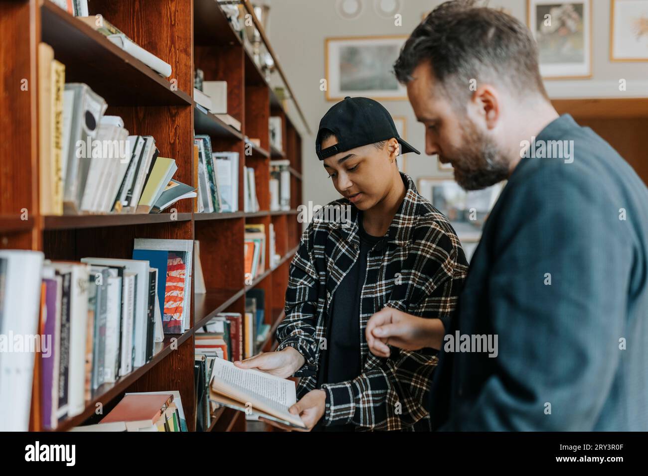 Young man discussing over book with professor in library Stock Photo ...
