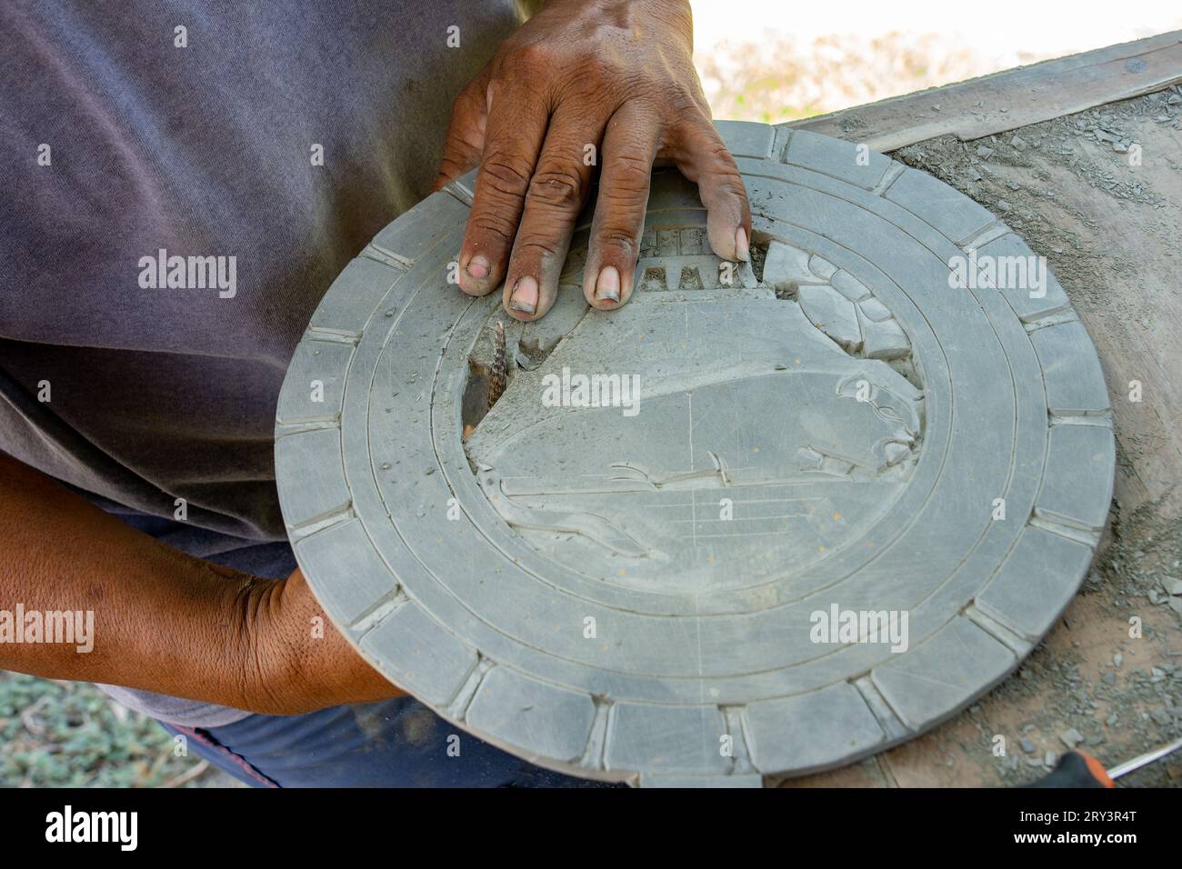 A Mayan craftsman carving a souvenir plaque of a Mayan pyramid on slate ...