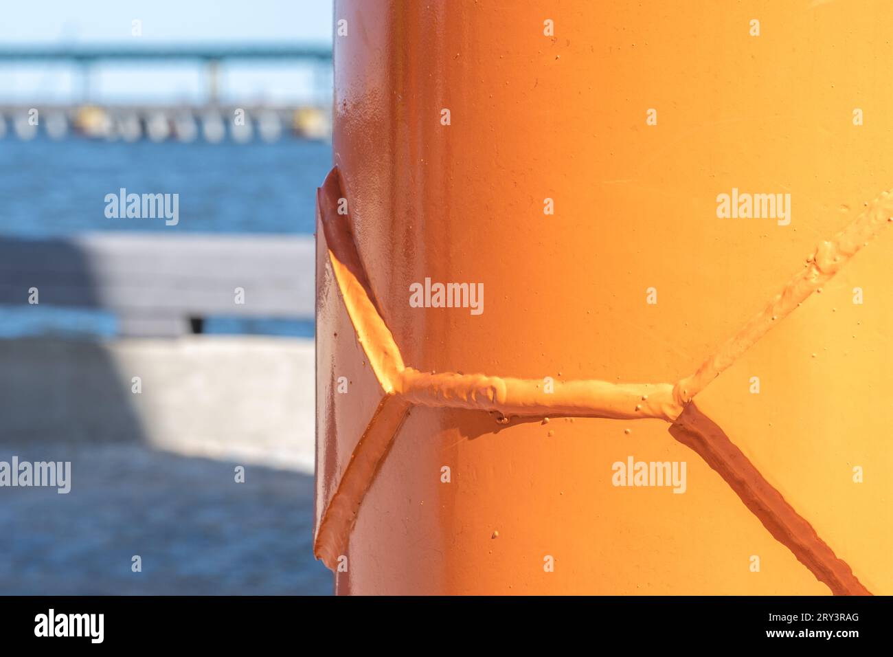 A huge metal bright orange tube on the seashore. In the background, a ...